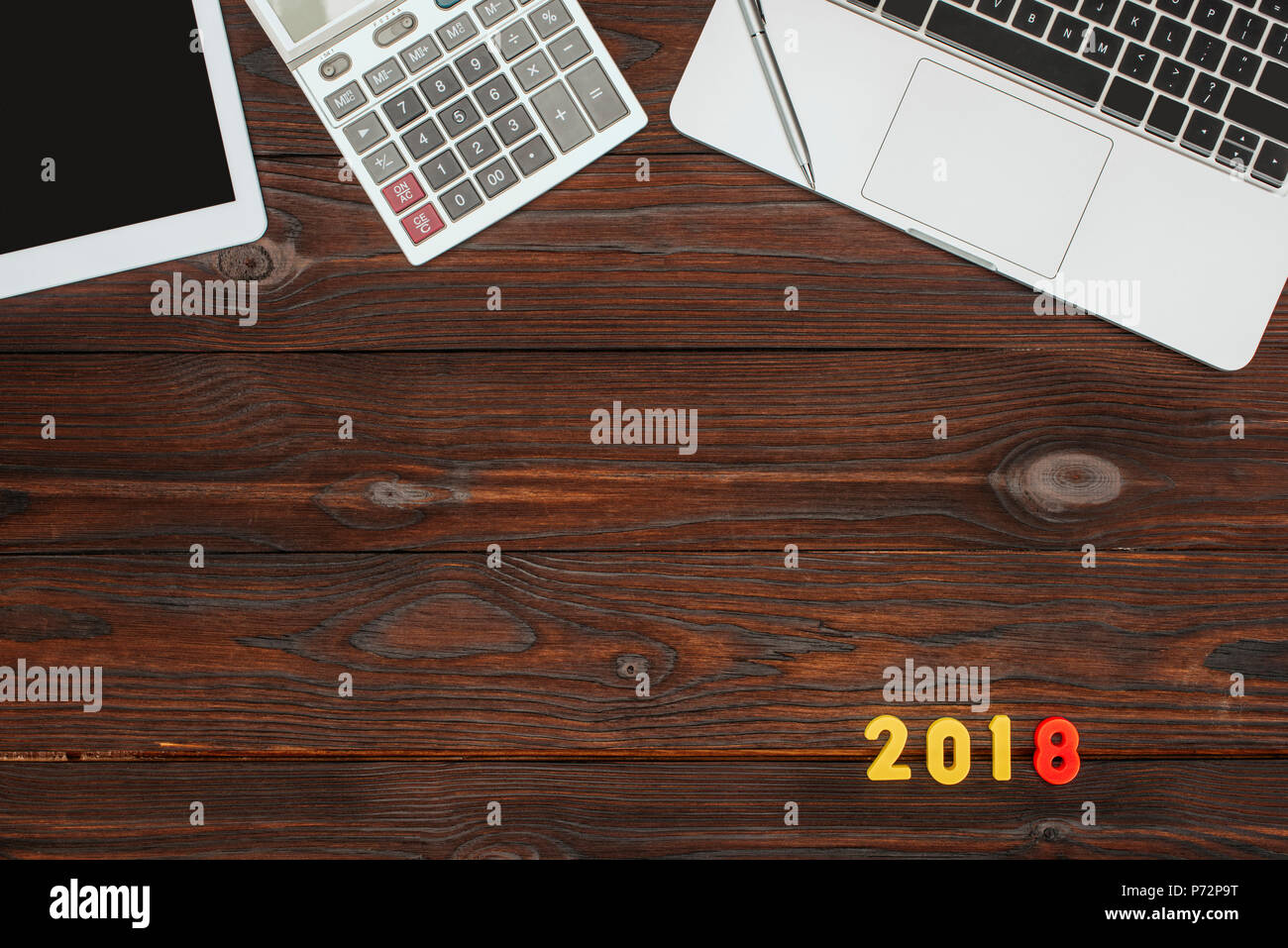 top view of laptop, tablet, calculator and 2018 numbers on wooden ...