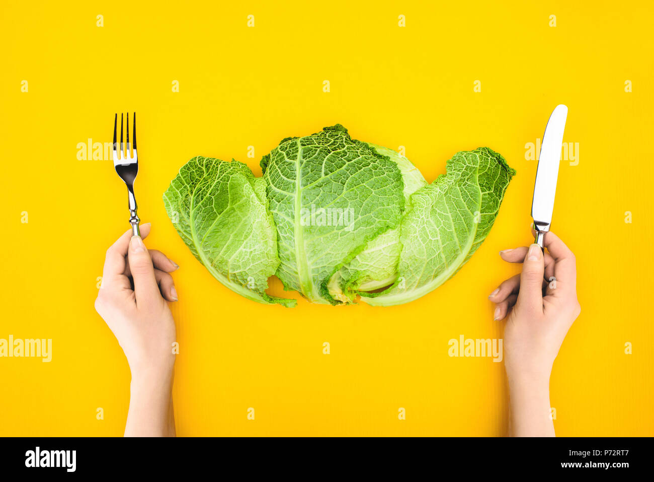 top view of person holding fork and knife while eating healthy cabbage ...