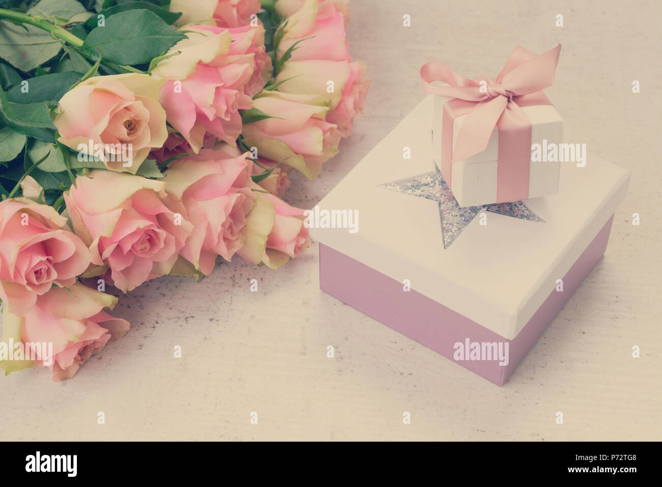 Pink roses bouquet with pile of gift boxes with pink ribbon, toned ...