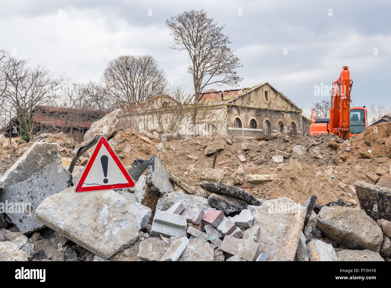 Red traffic triangle warning sign stands in front of destroyed building ...