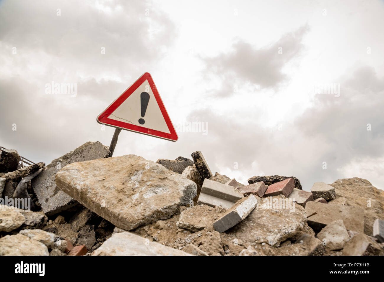 Red traffic triangle warning sign stands in front of destroyed building ...
