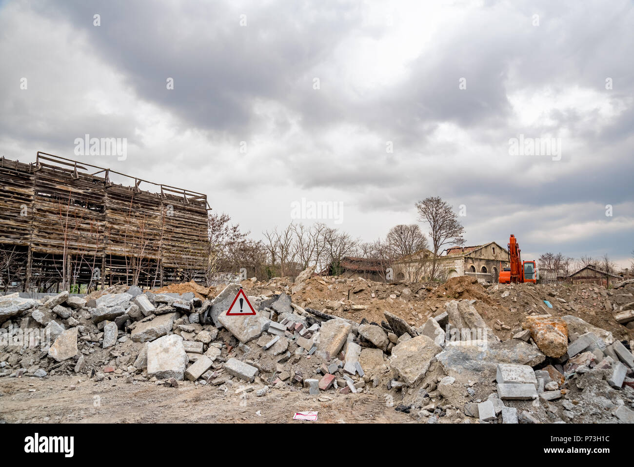 Red traffic triangle warning sign stands in front of destroyed building ...