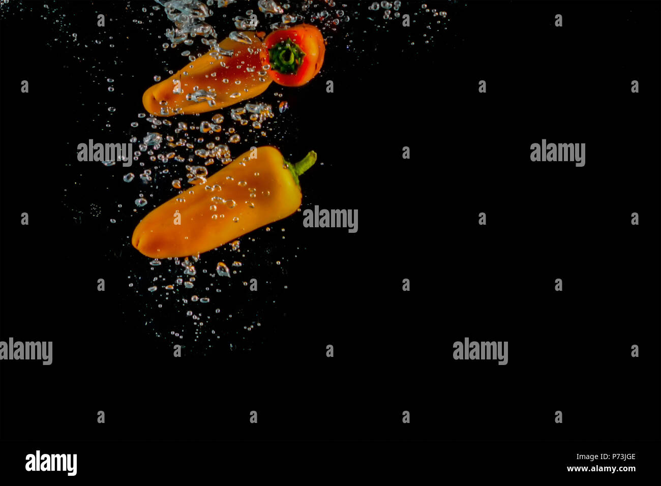 red green capsicum water splash black back ground Stock Photo - Alamy