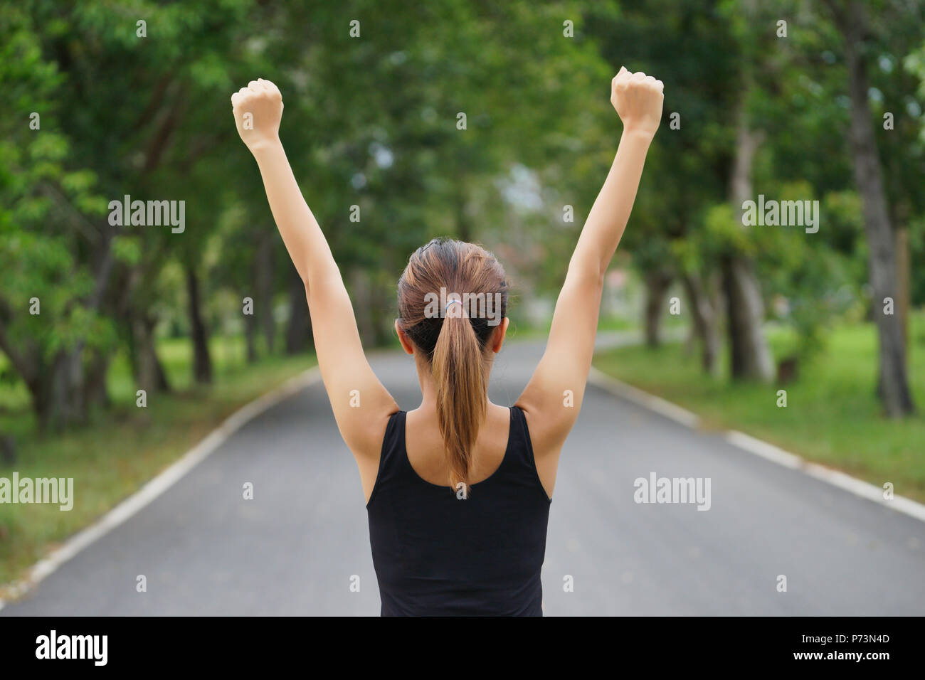 Successful woman raising arms after cross track running on summer ...