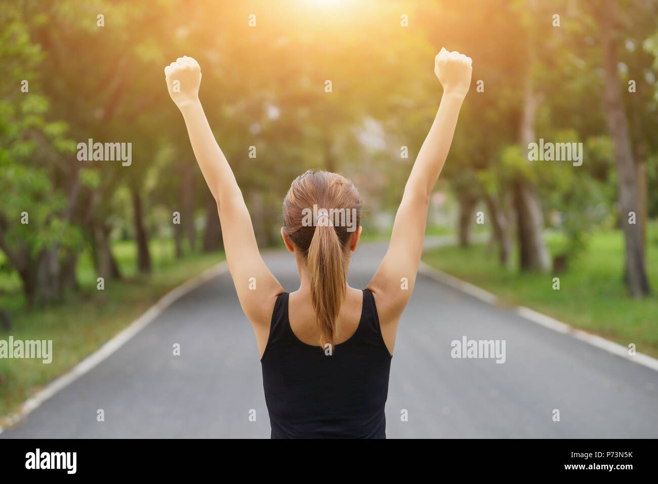 Successful woman raising arms after cross track running on summer ...