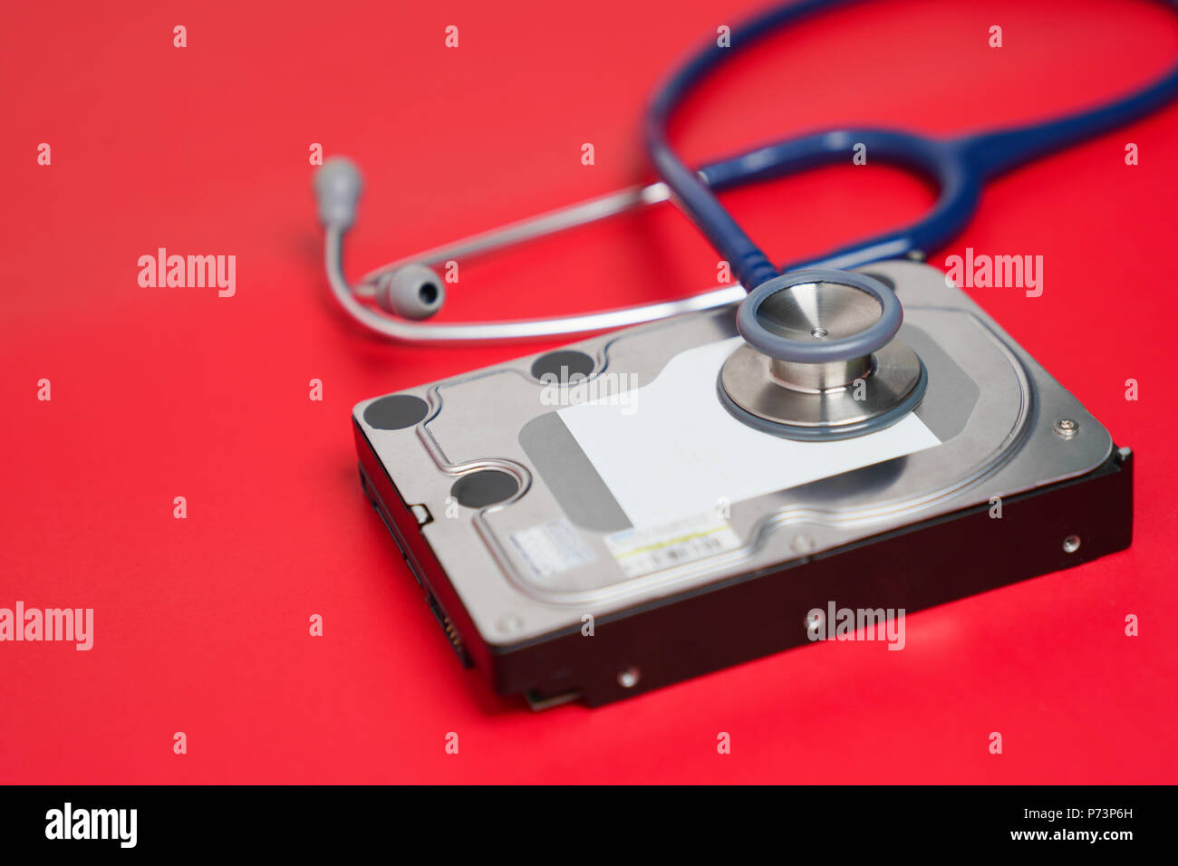 Stethoscope and hard disk drive on red background. Computer hardware ...