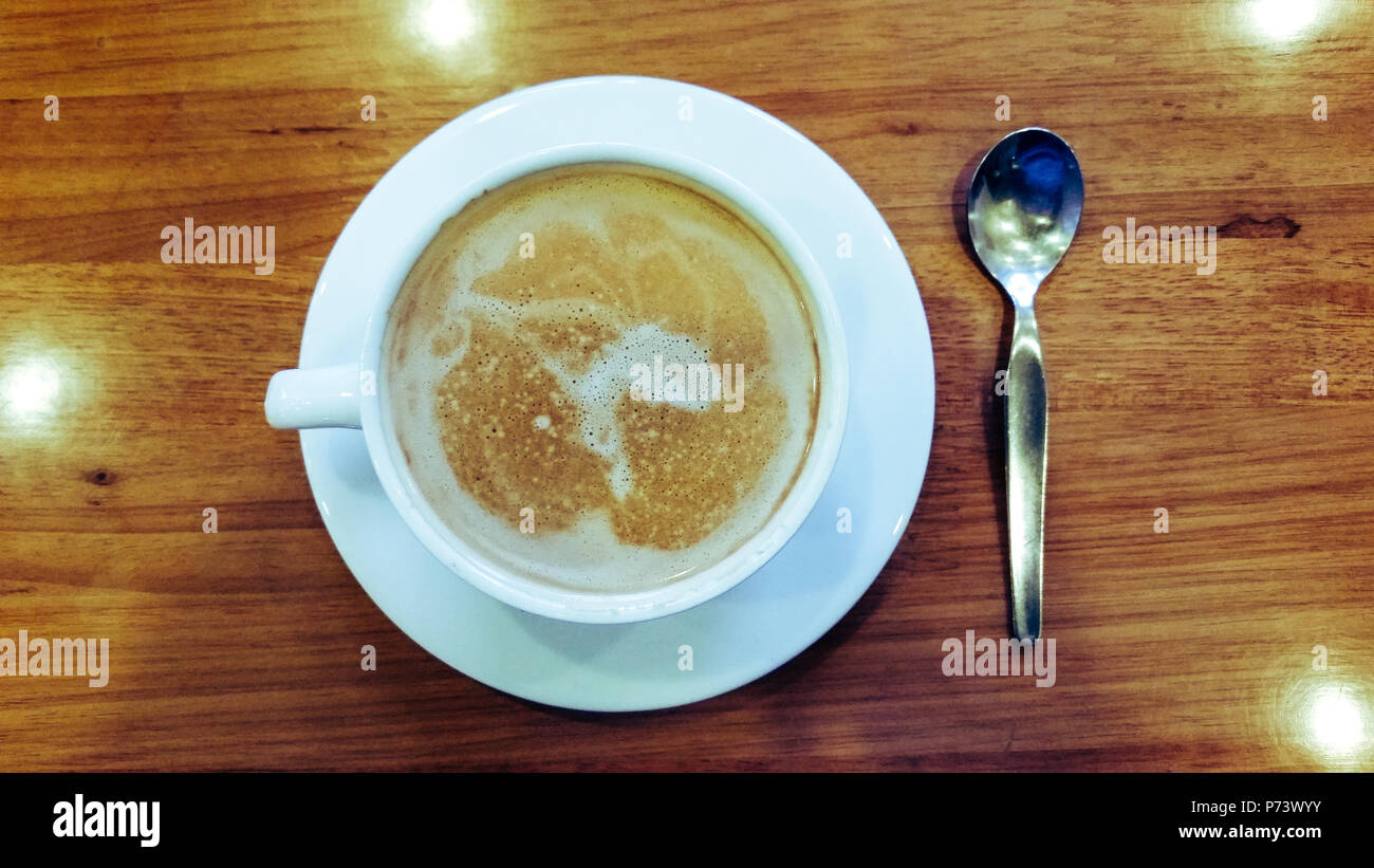 Top view of espresso cup, spoon and an illuminated wooden background ...