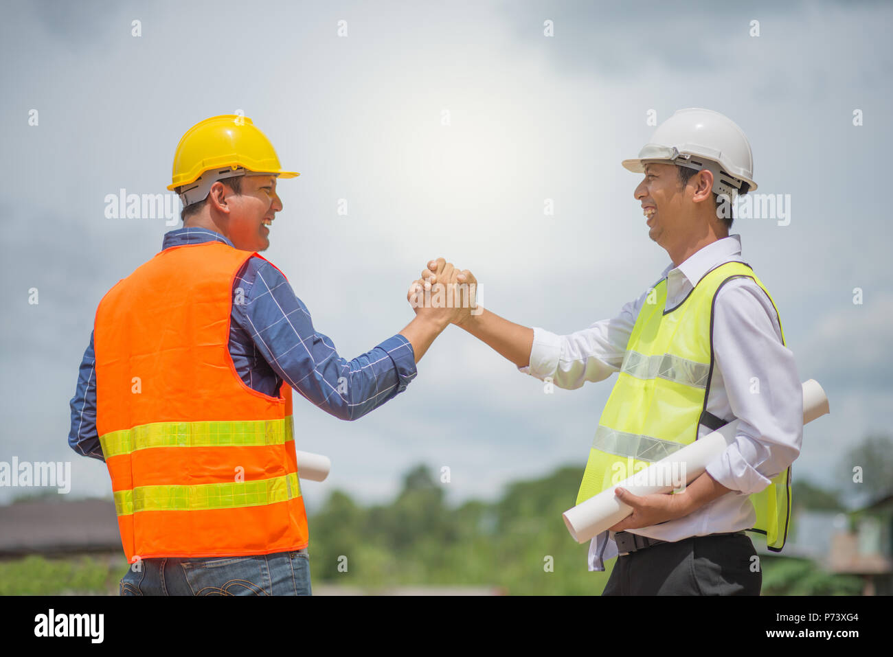 Handsome construction workers in protective helmets and vests are ...