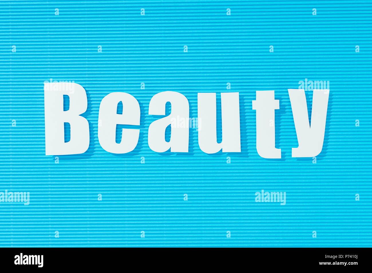 white word beauty on bright blue striped background, beauty concept ...