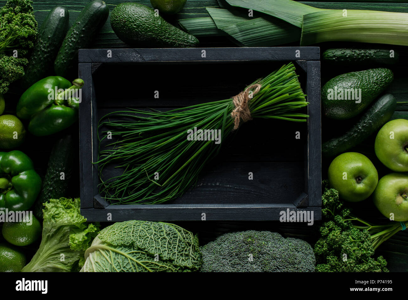 top view of chives in wooden box between green vegetables, healthy ...