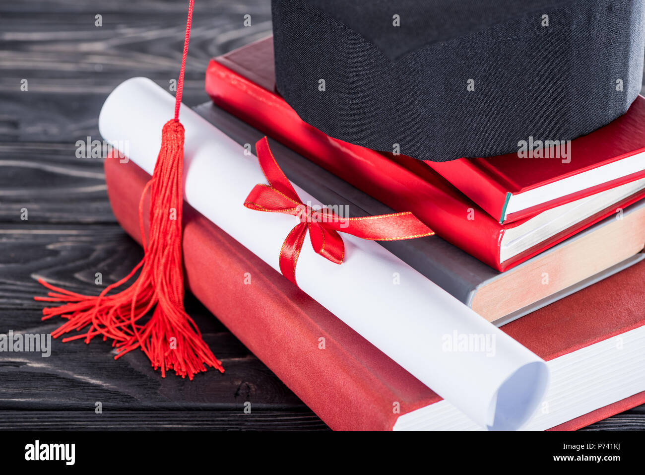 Graduation concept diploma and graduation cap on stack of books Stock ...