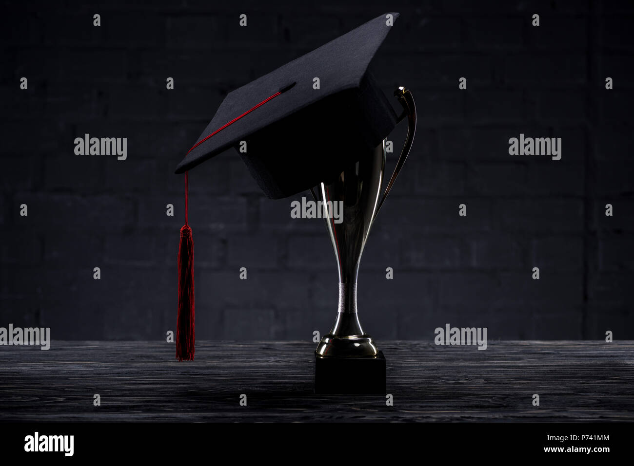 Graduation cap on trophy cup on wooden table Stock Photo - Alamy