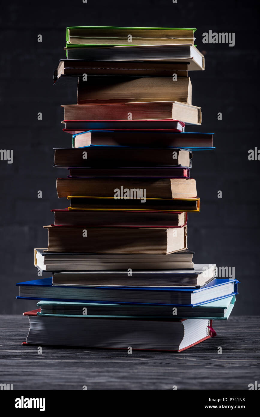 High stack of books on dark wooden background Stock Photo - Alamy