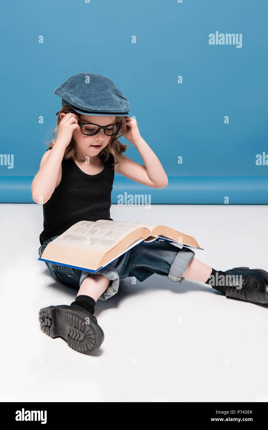 casual kid girl reading book while sitting on the floor Stock Photo - Alamy