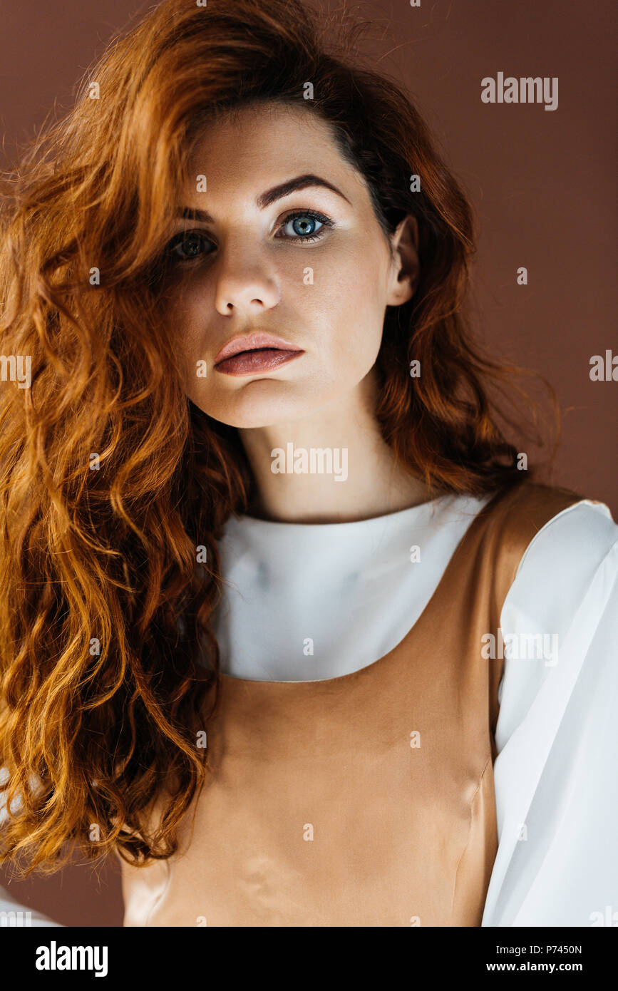 Beautiful young girl in beige dress isolated on brown background Stock ...
