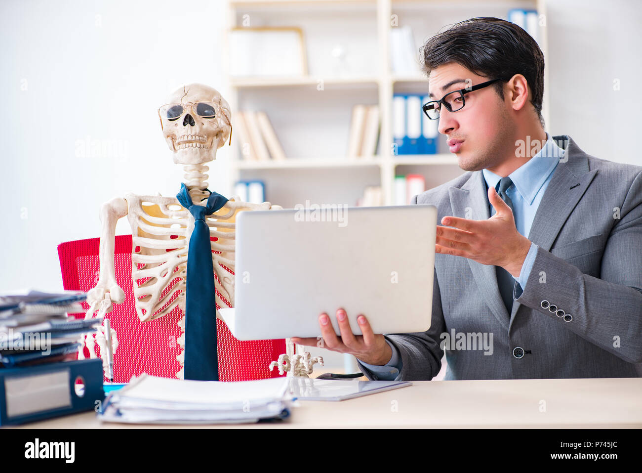 Businessman working with skeleton in office Stock Photo - Alamy