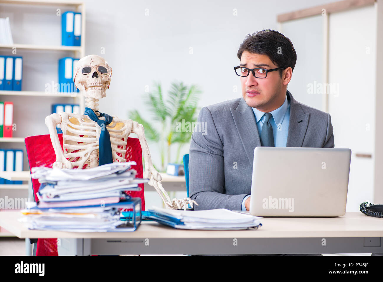 Businessman working with skeleton in office Stock Photo - Alamy