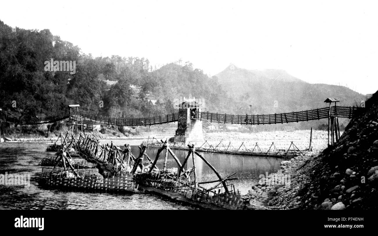 Chinese built suspension bridge, boats docked at pier in foreground ...