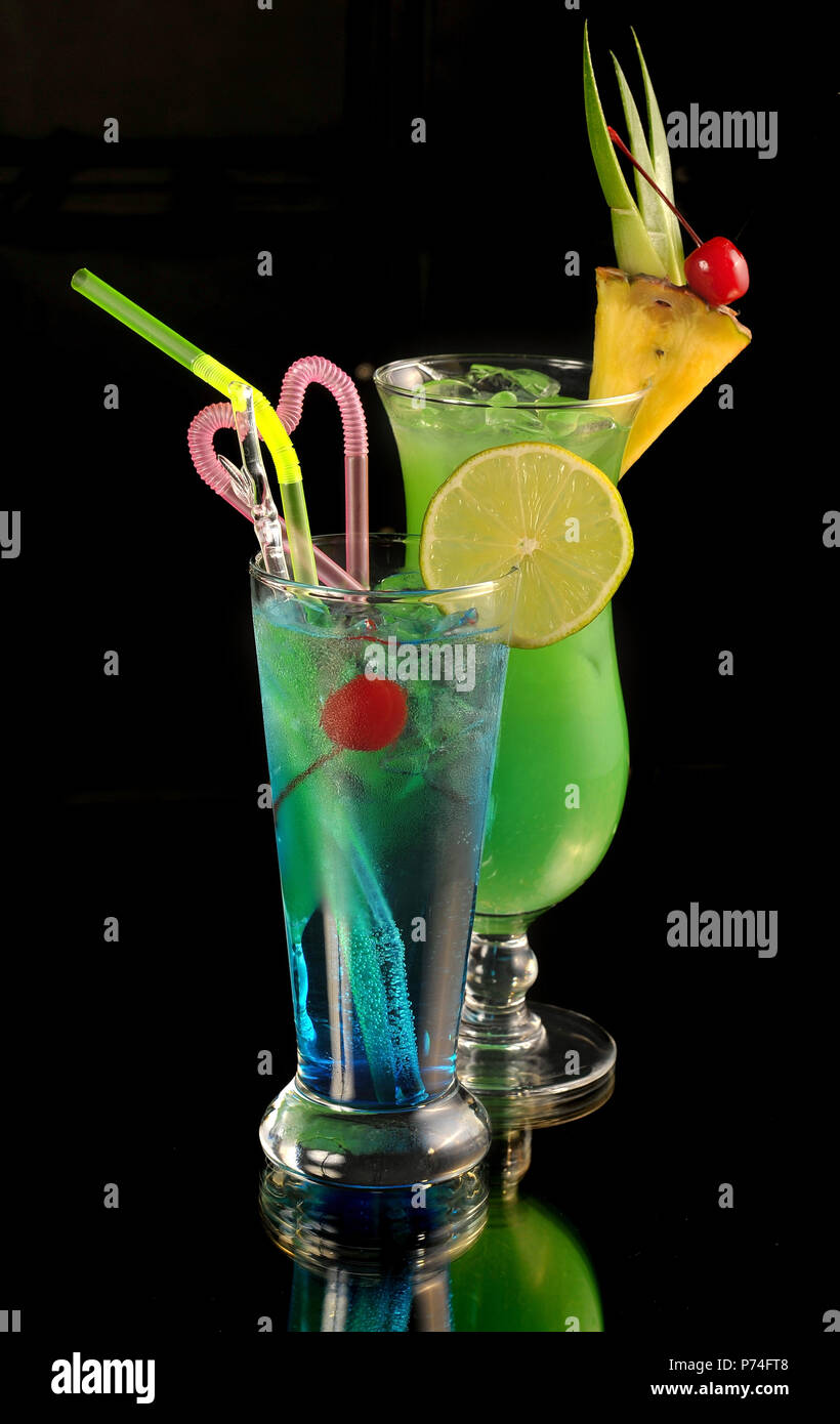green cocktail with pineapple and blue cocktail with ice and lime on ...