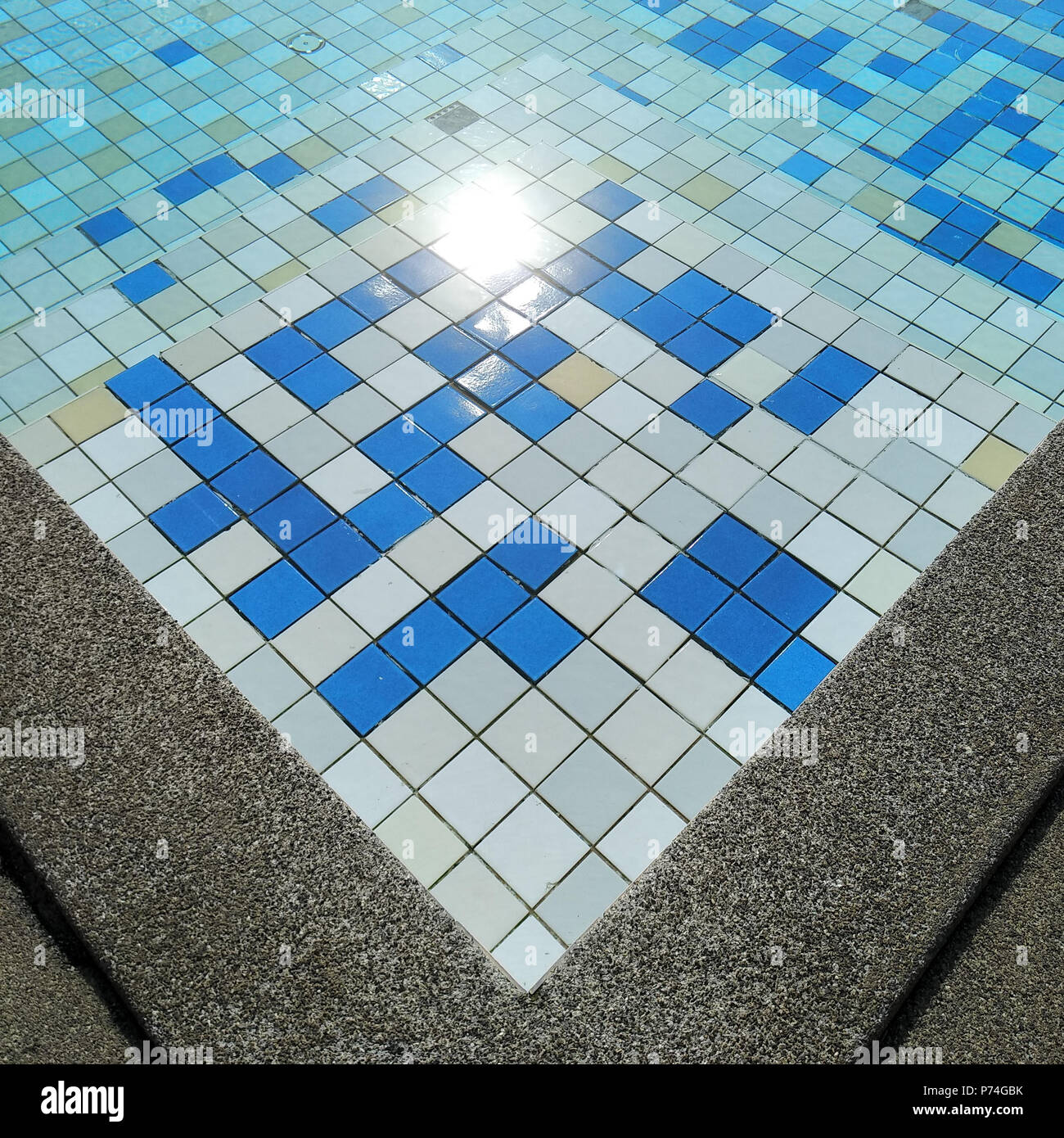 Blue and white tiles on the bottom of the pool with sun reflection ...
