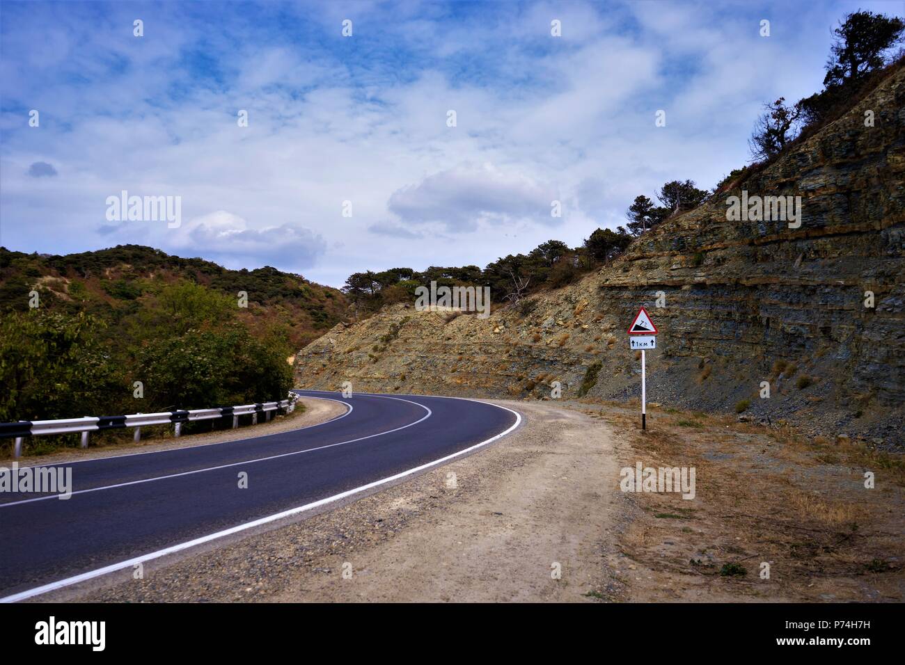 asphalt road with turn past a beautiful hill Stock Photo - Alamy