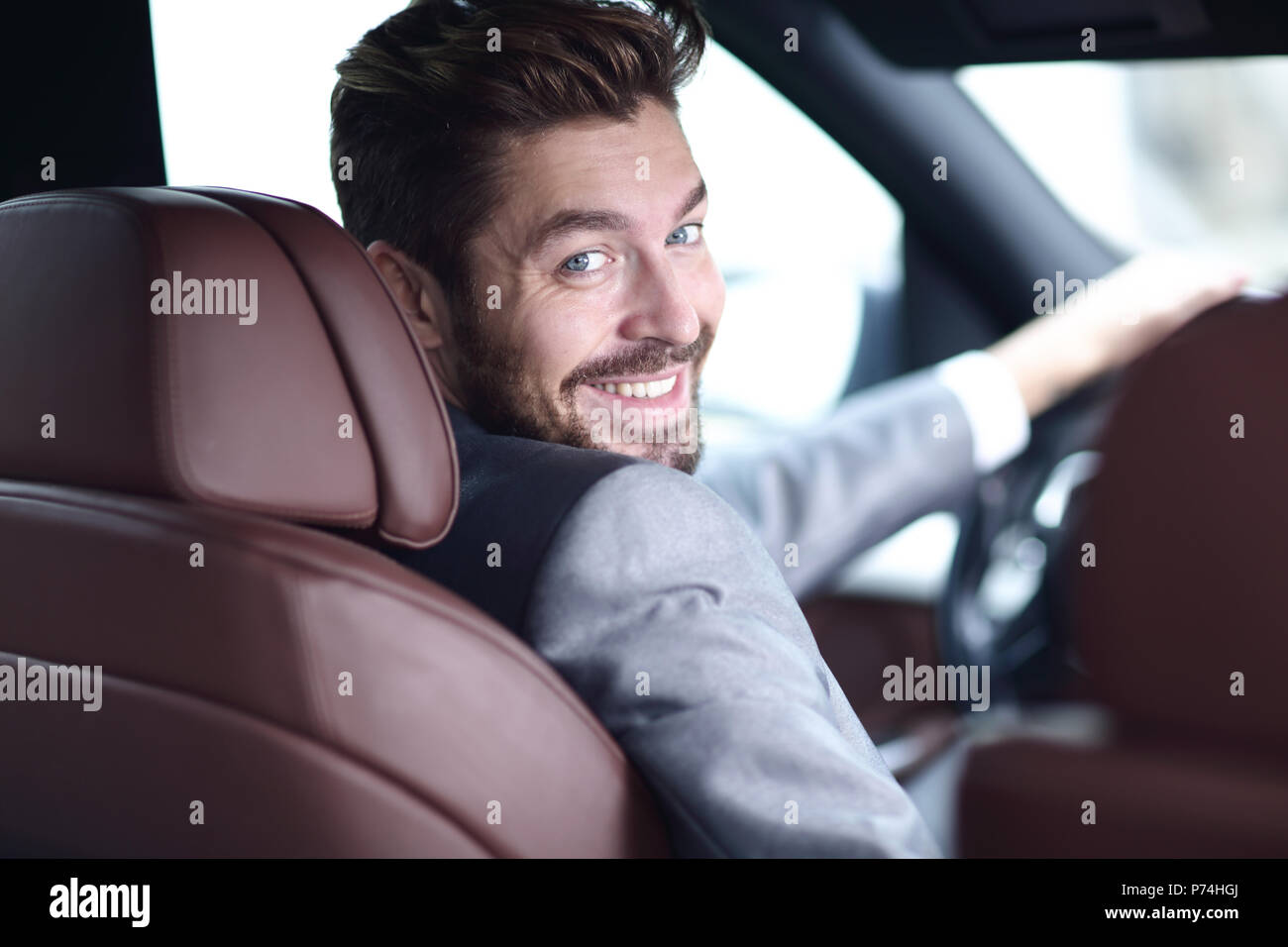 rear view, young man driving his car, looking at camera Stock Photo - Alamy