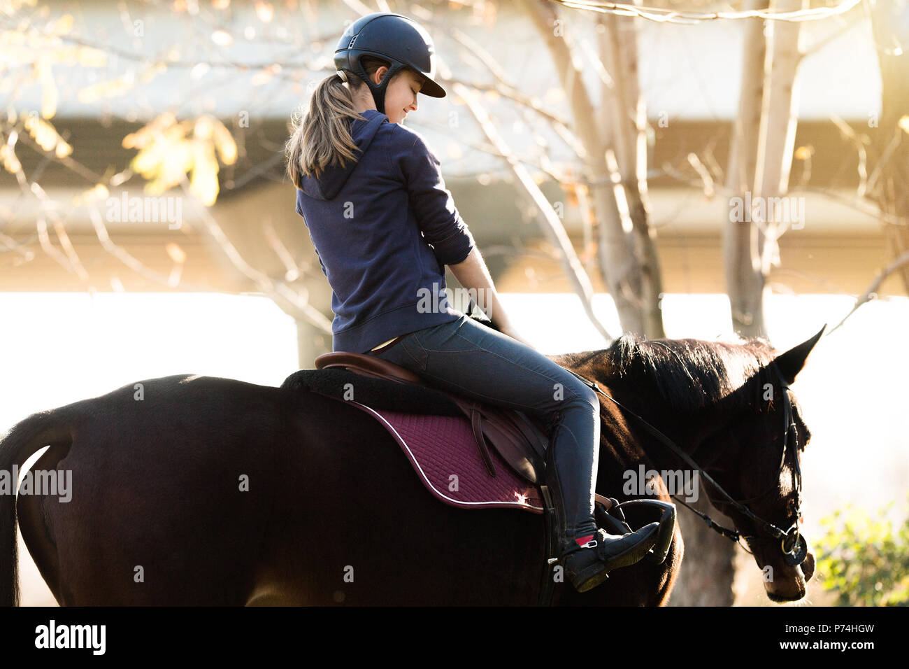 Young pretty girl - riding a horse with backlit leaves behind Stock ...