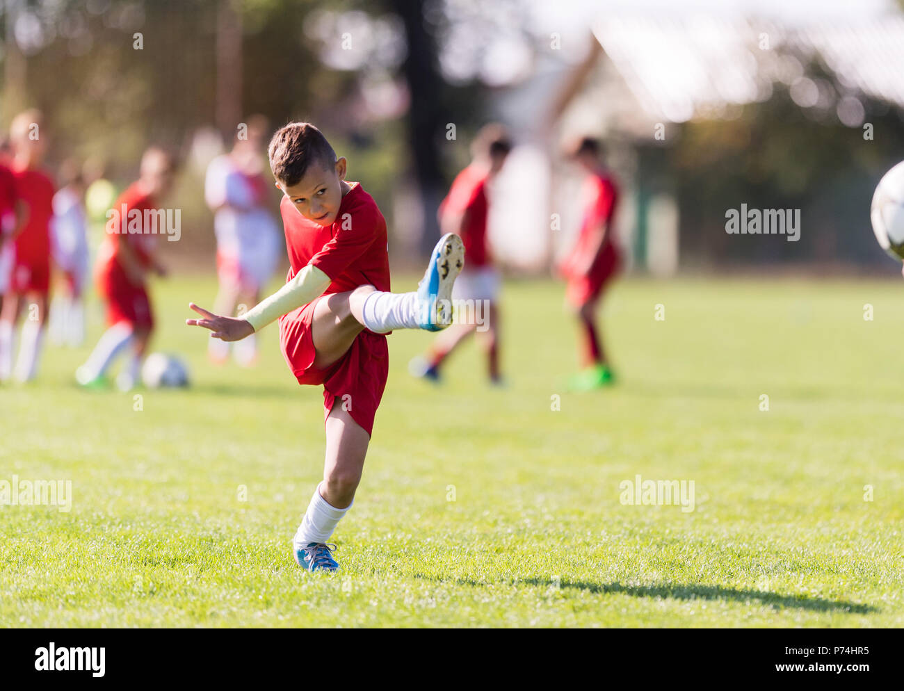 Boy kicking football on the sports field during soccer match Stock ...
