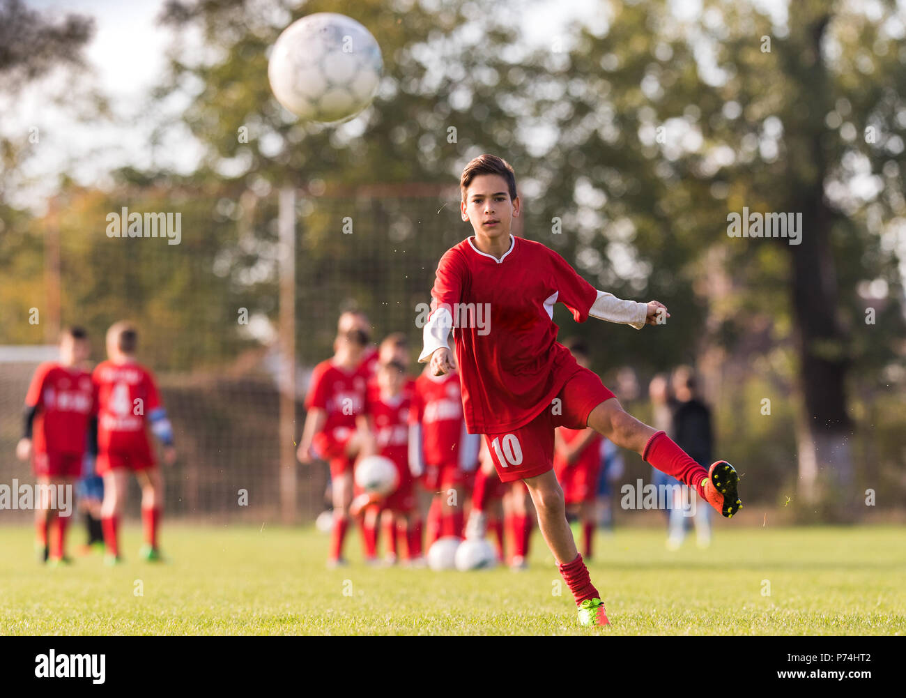 Boy kicking football on the sports field during soccer match Stock ...