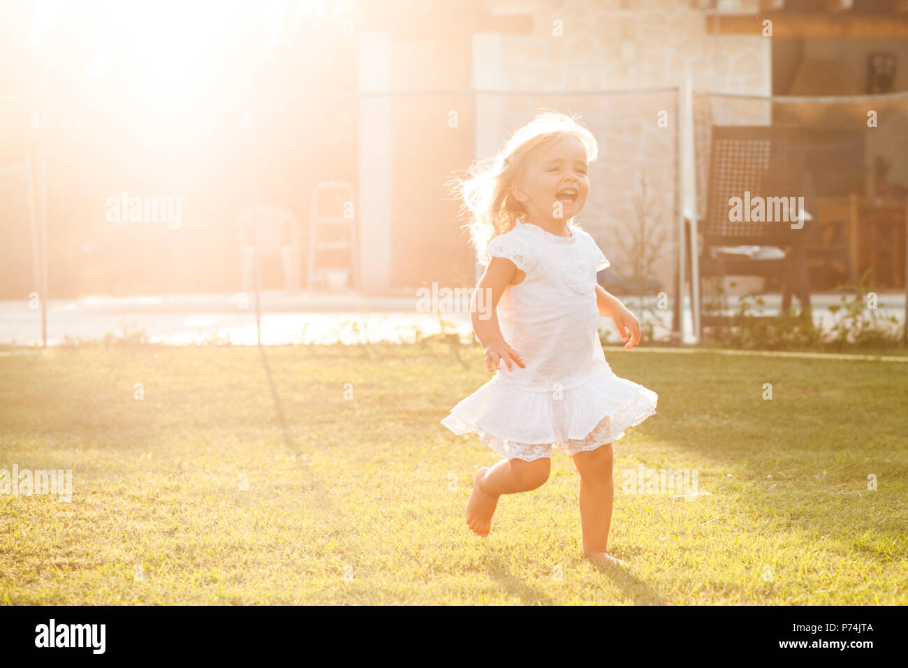 Happy little girl running in the yard Stock Photo - Alamy