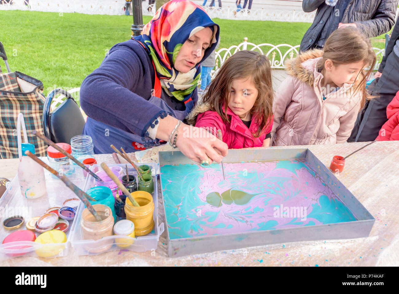 Unidentified woman teaches kid Ebru art or marbling. Traditional ...