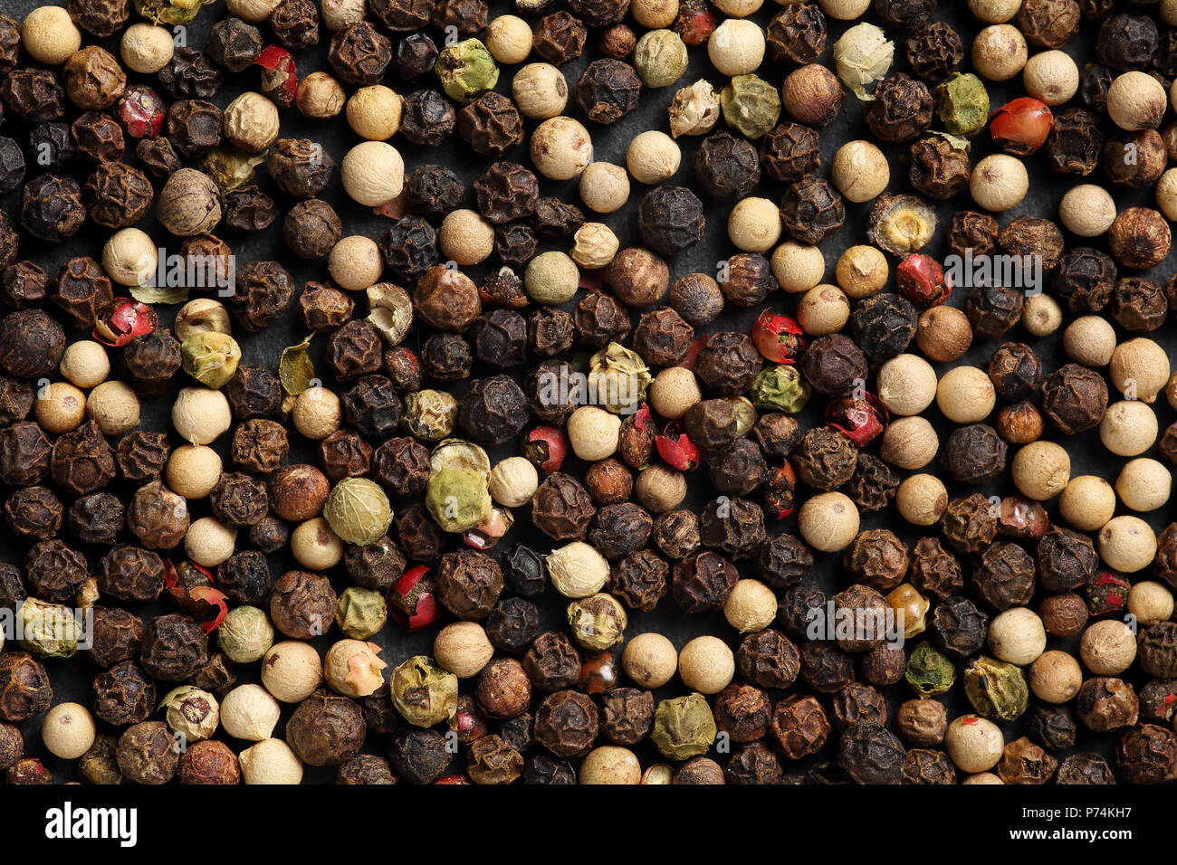 Extreme close up of blend peppercorn mix on a black stone board. Macro ...