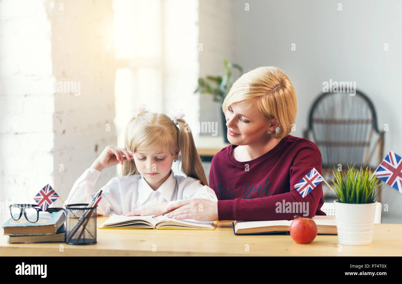Female educator of English and smart girl, working table with books ...