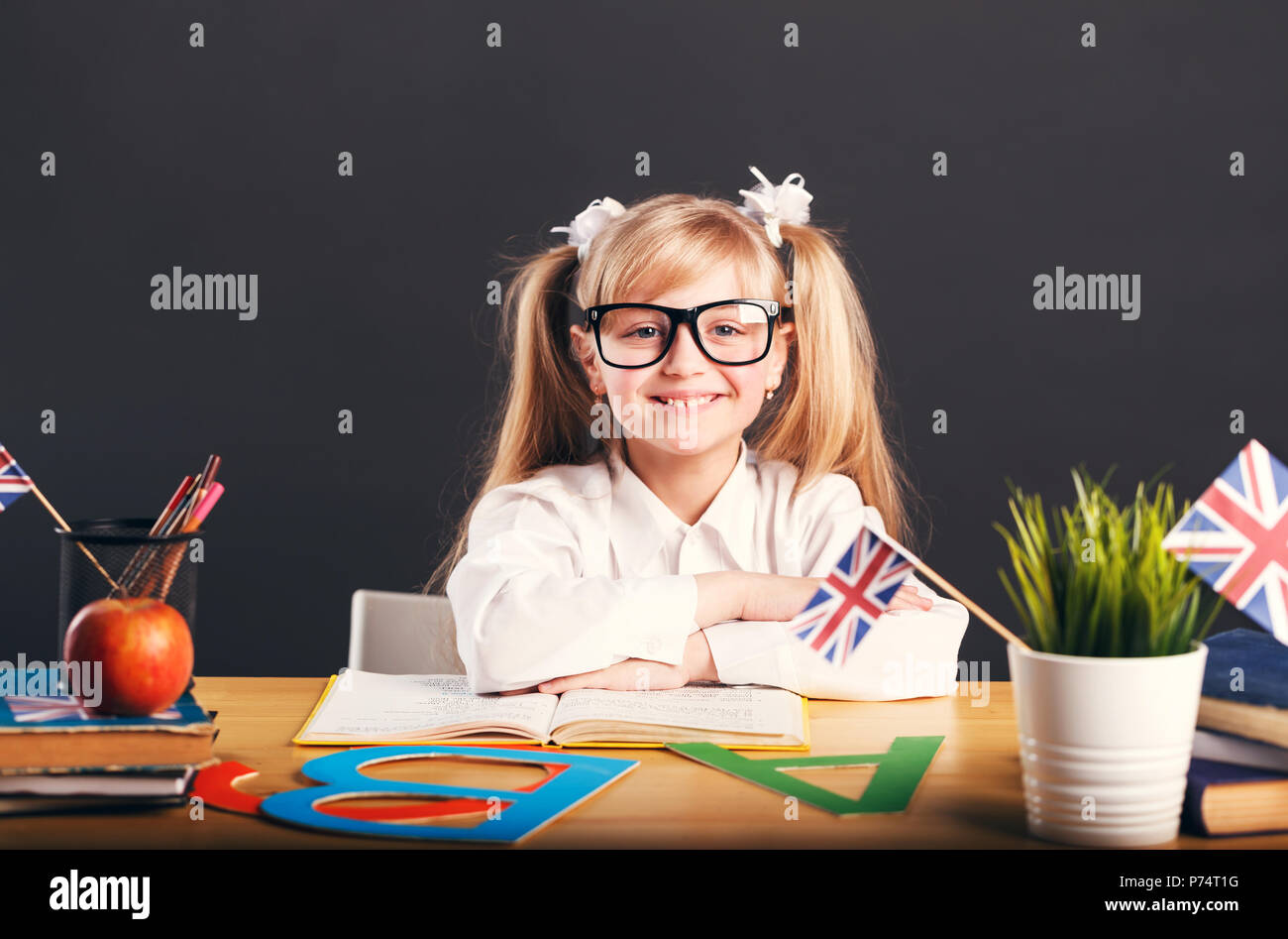 Happy smiling girl learning English language, working table with books ...