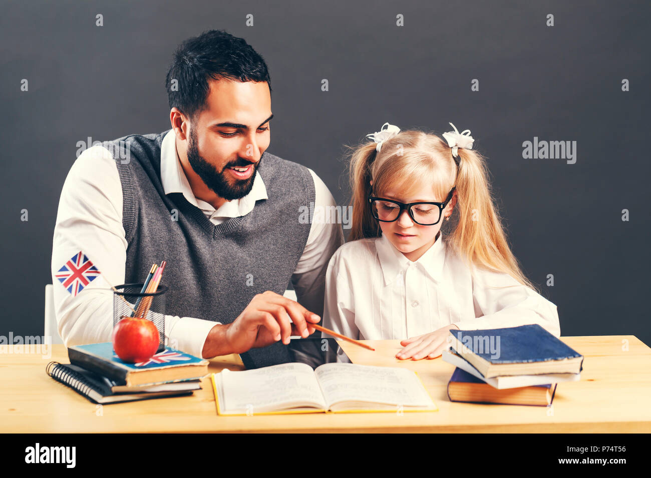 Intelligent male teacher in gray vest explaining new material to the ...