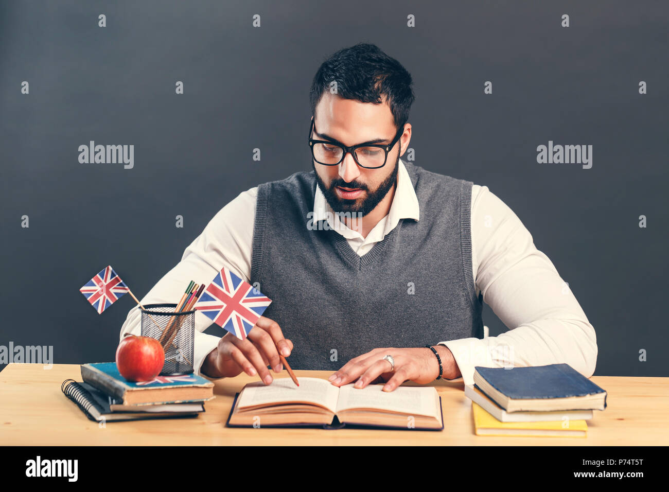 Handsome man in gray vest practising English reading skills,, indoor ...