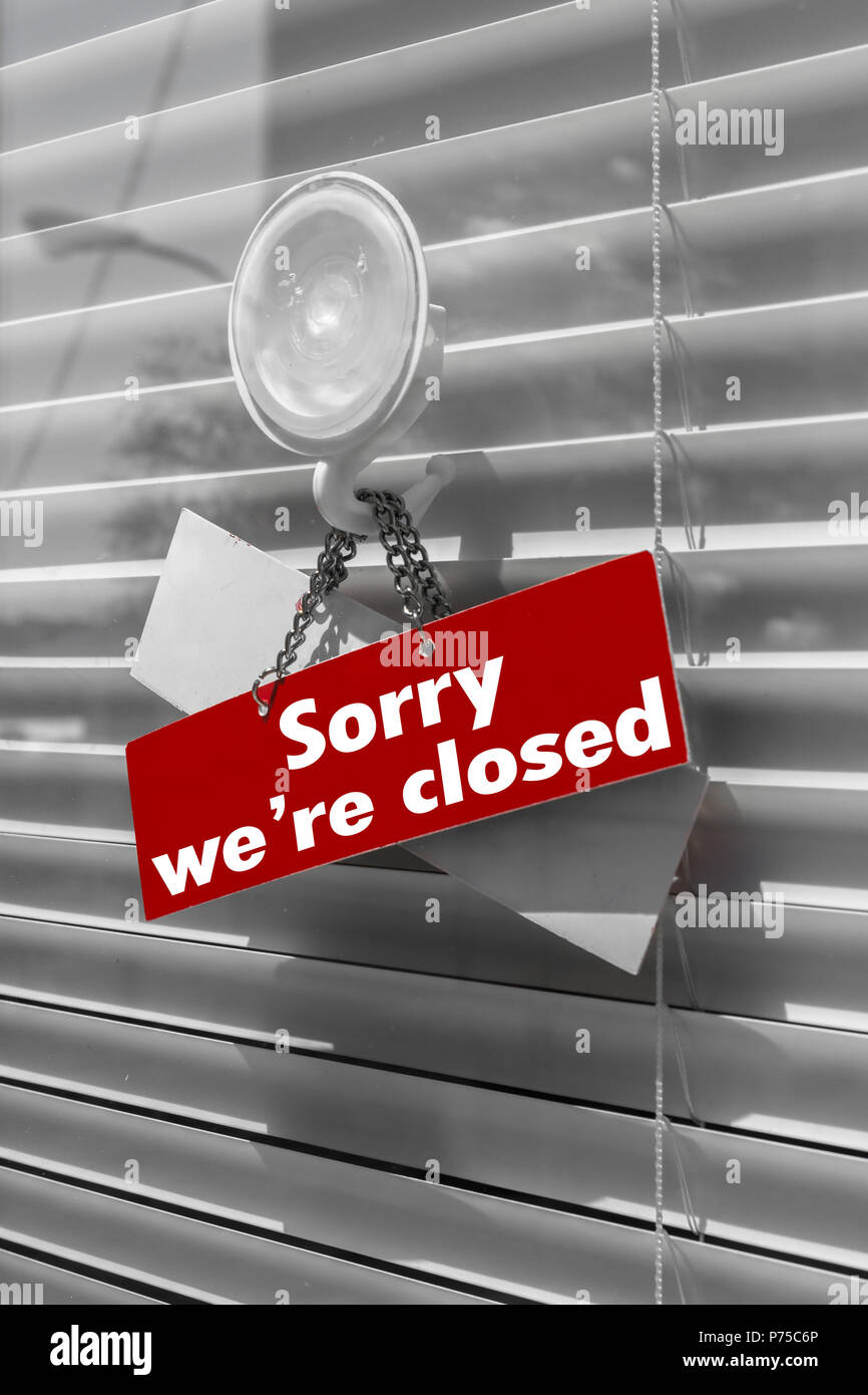 Sign saying "sorry we're closed" on a glass door with a white, closed ...