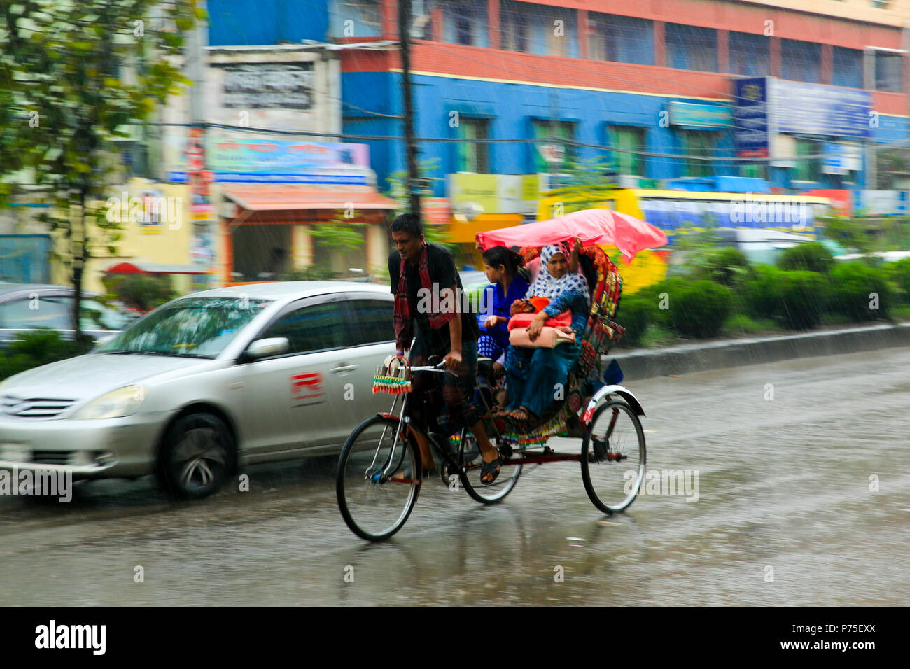 A rickshaw puller carries his passengers in the rainy day, Dhaka ...
