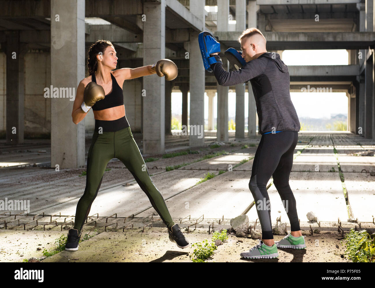 Young athlete couple doing kick boxing exercise in an old abandoned ...