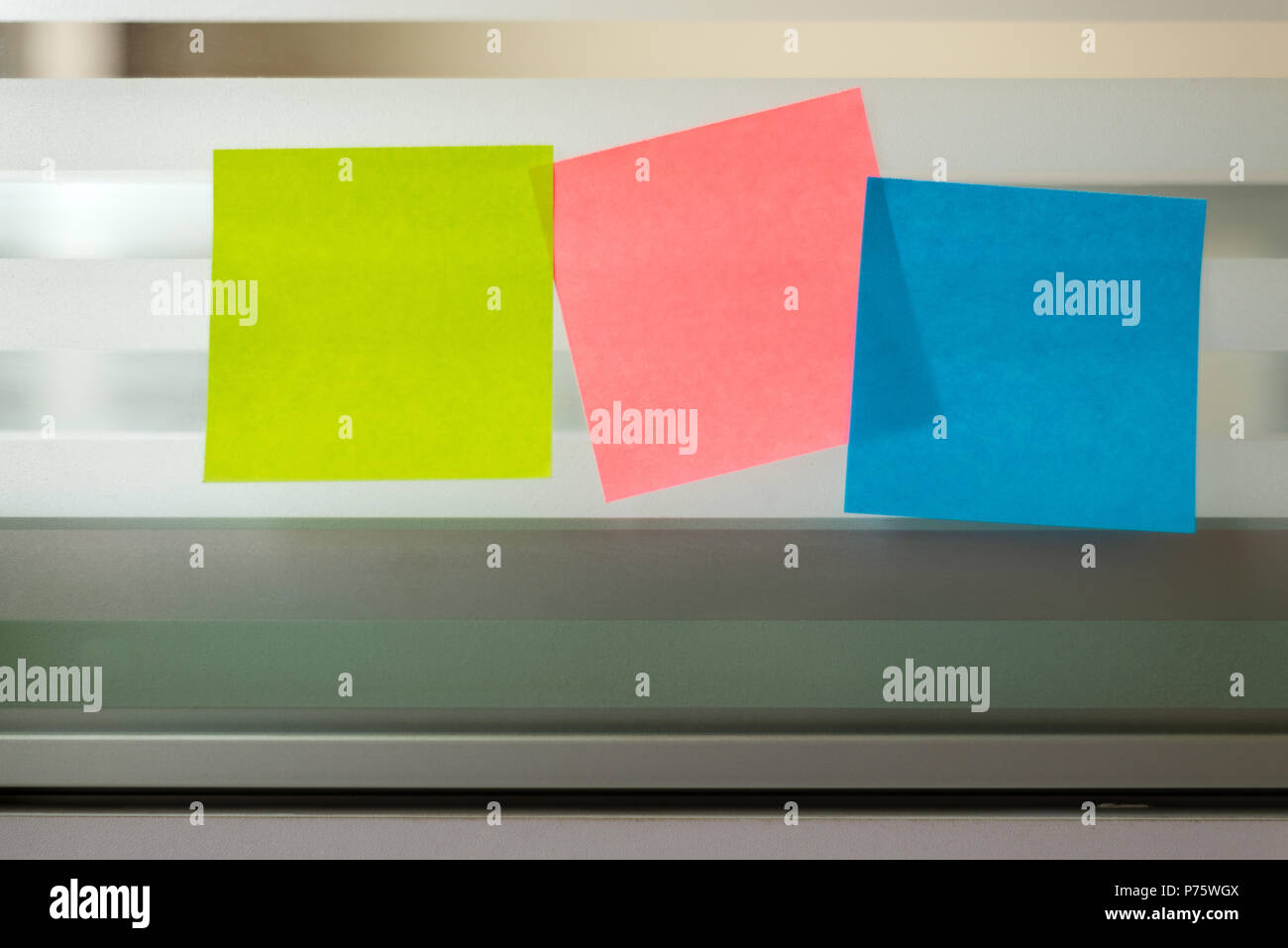 Three colored sticky notes over glass screen of a bench desk Stock ...