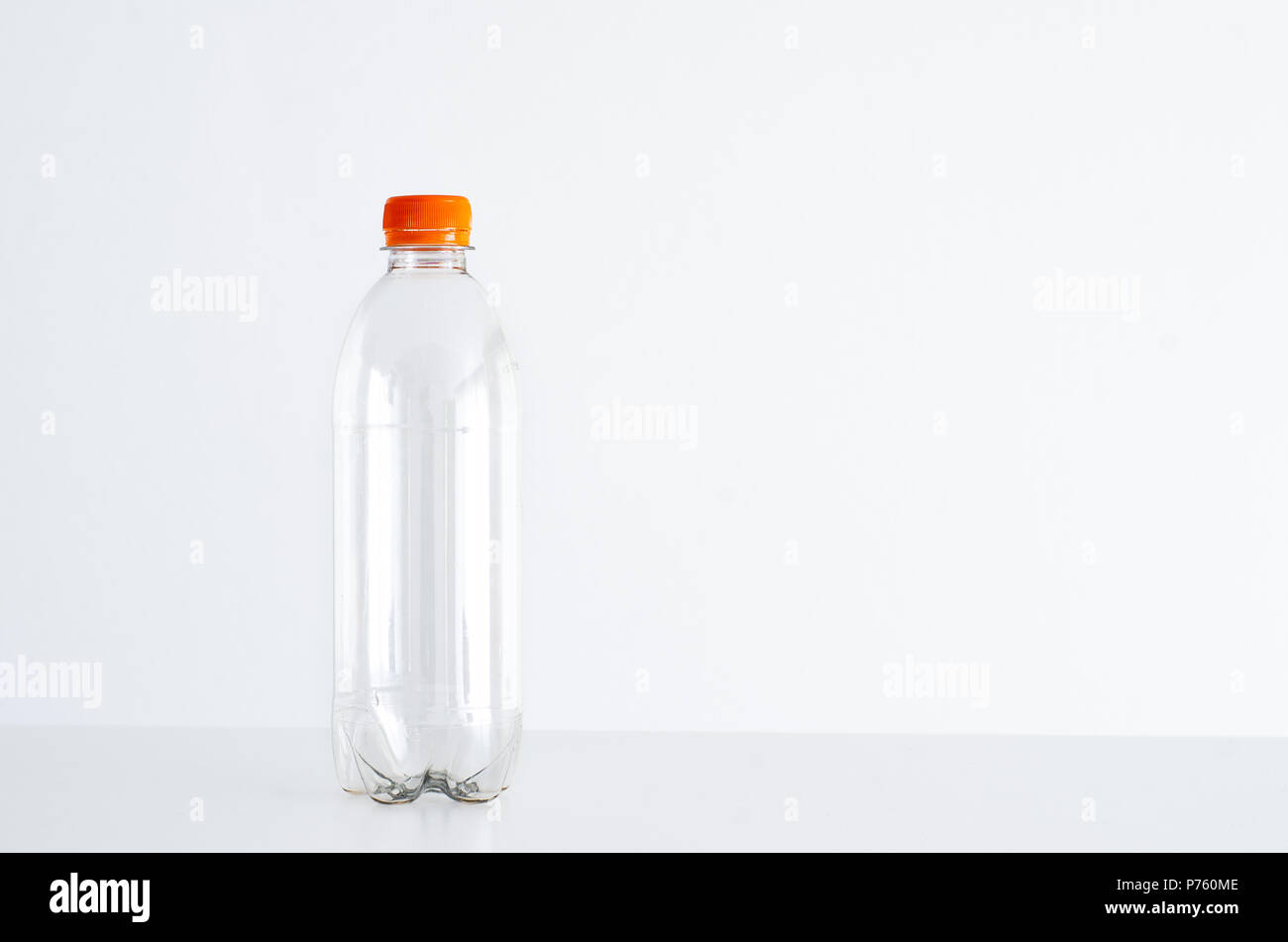Single empty plastic water bottle isolated against bright white ...