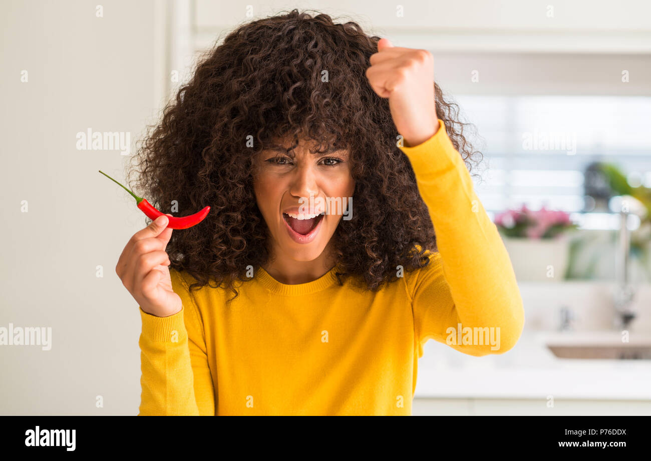 African american woman eating red hot chili pepper annoyed and ...