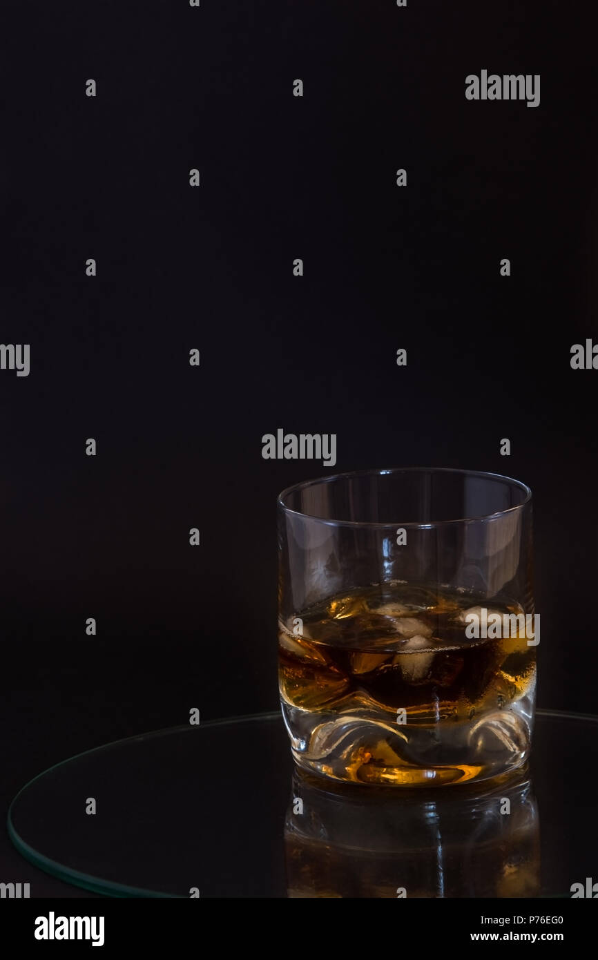 Glass of brandy served with ice on dark background Stock Photo - Alamy
