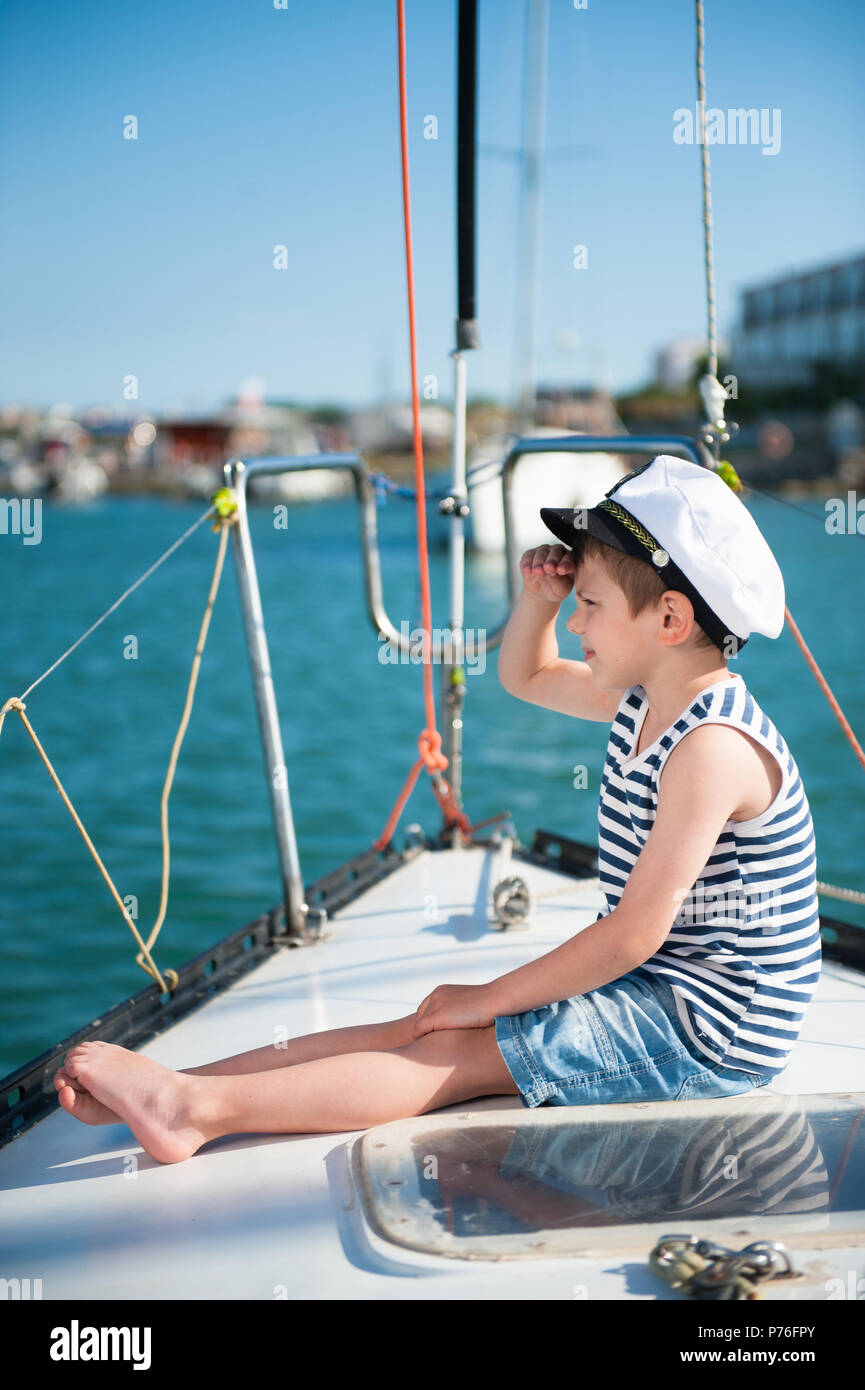 cute little kid in captain cap looking far ahead holding hand above his ...