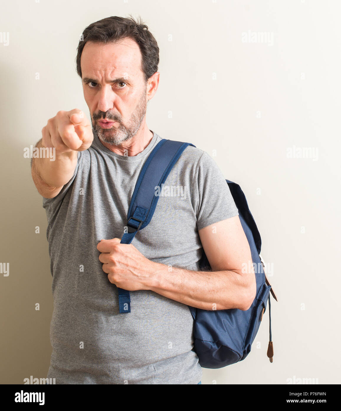 Senior man using backpack pointing with finger to the camera and to you ...
