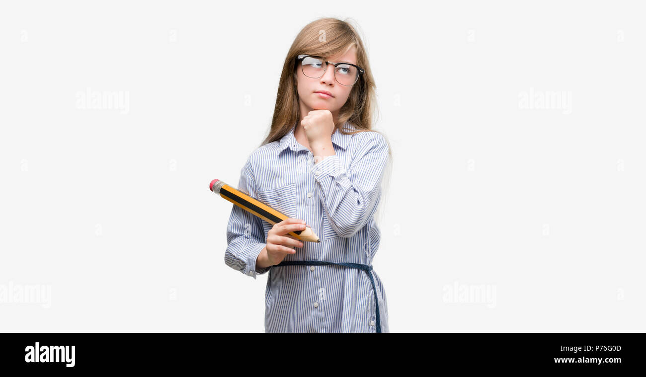 Young blonde child holding big pencil serious face thinking about ...