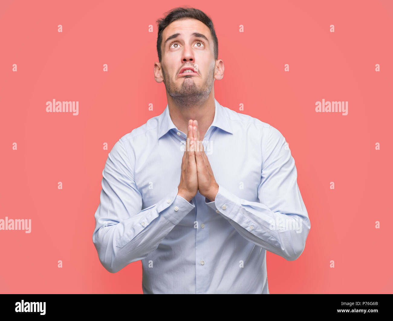Handsome young businessman begging and praying with hands together with ...