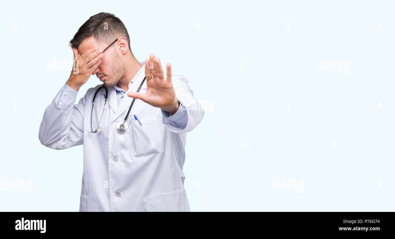 Handsome young doctor man covering eyes with hands and doing stop ...
