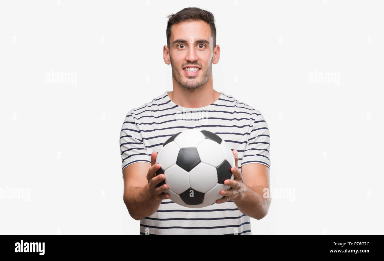 Handsome young man holding soccer football with a happy face standing ...