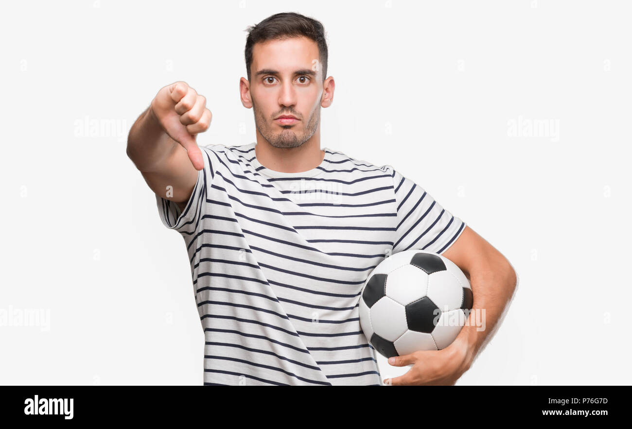 Handsome young man holding soccer football with angry face, negative ...